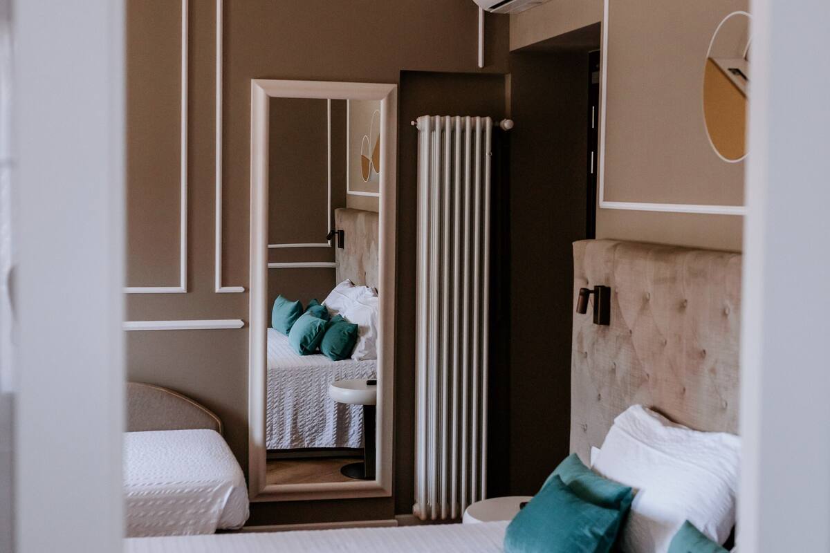 Quarto com cama, espelho e janela.