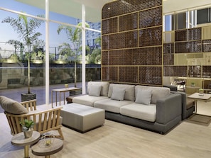 Uma sala de estar moderna com sofá, mesa de centro e cadeiras, uma parede decorativa e vista para o exterior.