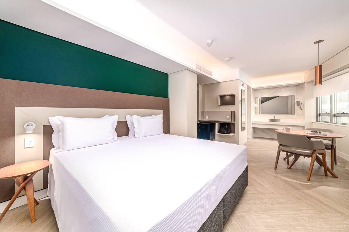 Quarto de hotel moderno com uma cama grande, uma escrivaninha e uma cadeira.