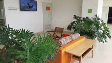 Uma área de recepção com sofá, mesa de madeira e plantas em vasos.