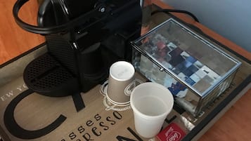 Máquina de café, duas chávenas de papel e um recipiente de vidro sobre um tabuleiro com publicidade de café.
