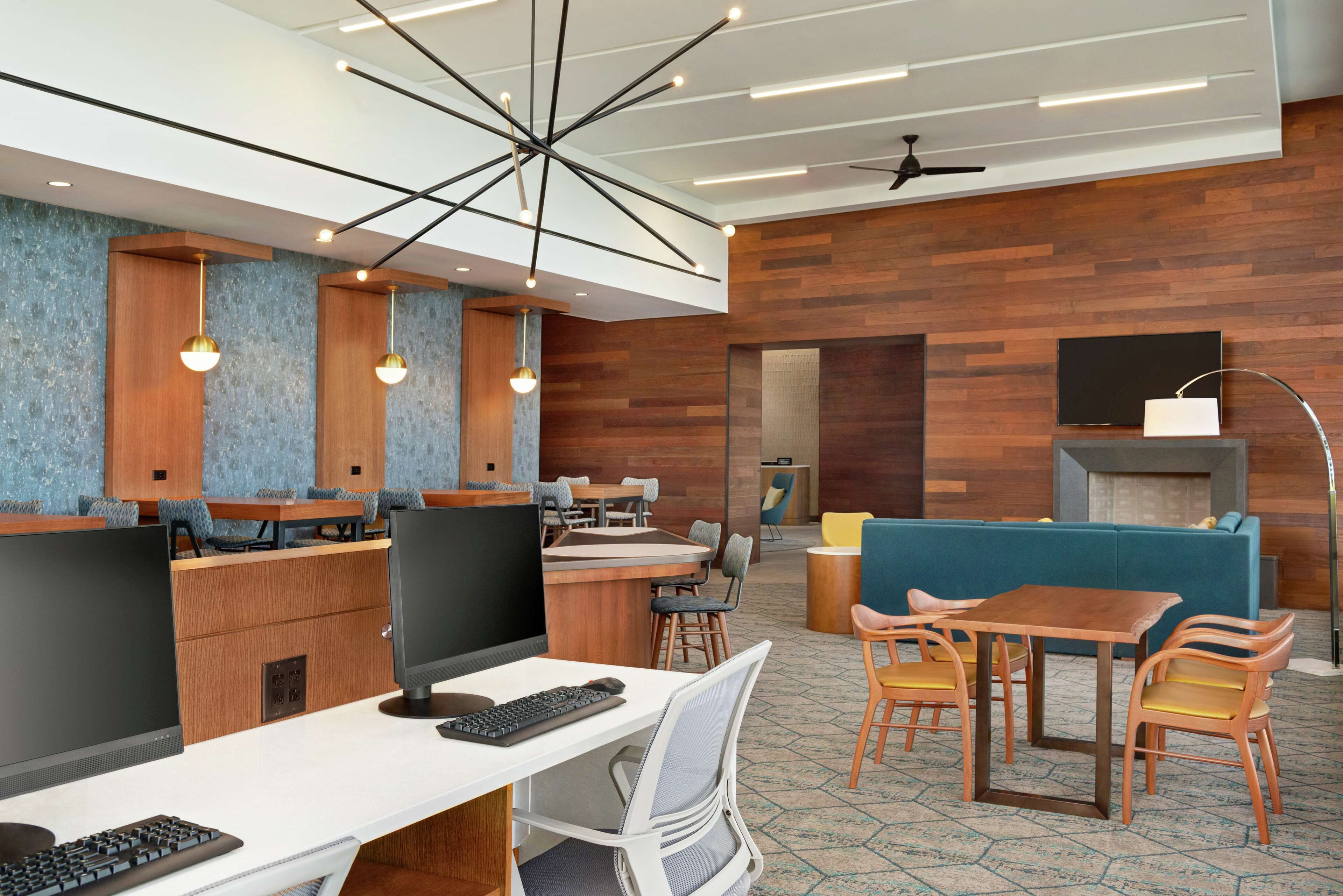 Um hall de hotel moderno com balcão de recepção, computadores, área de estar e lareira.