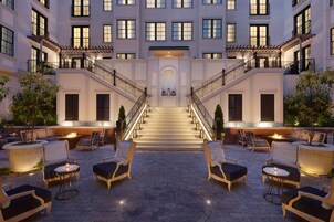 Um hotel com uma escadaria central, área de estar ao ar livre e várias janelas.