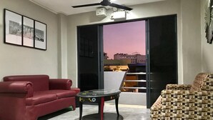 Uma sala de estar com um sofá vermelho, um sofá estampado e uma pequena mesa redonda.