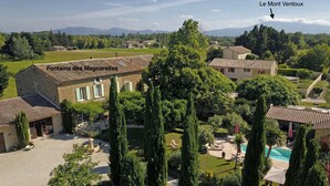Uma grande propriedade com piscina, ciprestes altos e vista para as montanhas.