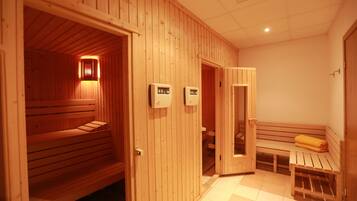 Sala de sauna com bancos de madeira, um banco com toalha e uma porta que dá para outro espaço.