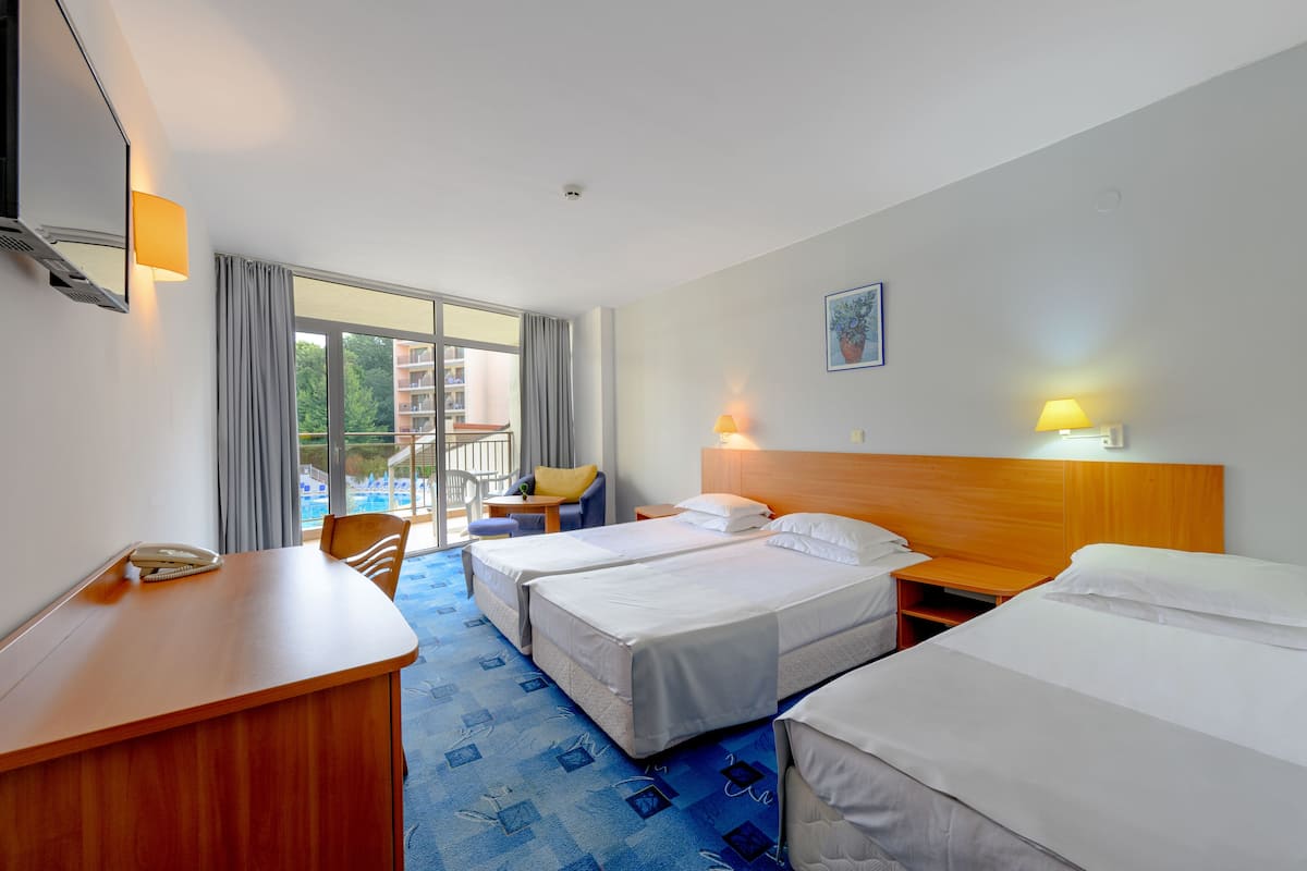 Quarto de hotel com duas camas, uma mesa, uma cadeira, uma mesinha e uma janela com vista para o exterior.
