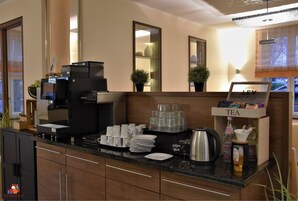 Uma cozinha moderna com um espaço para café, incluindo máquina de café, xícaras e um espaço para chá.