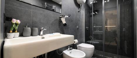 Casa de banho moderna com uma grande pia, duas sanitas, cabine de duche em vidro e plantas decorativas.