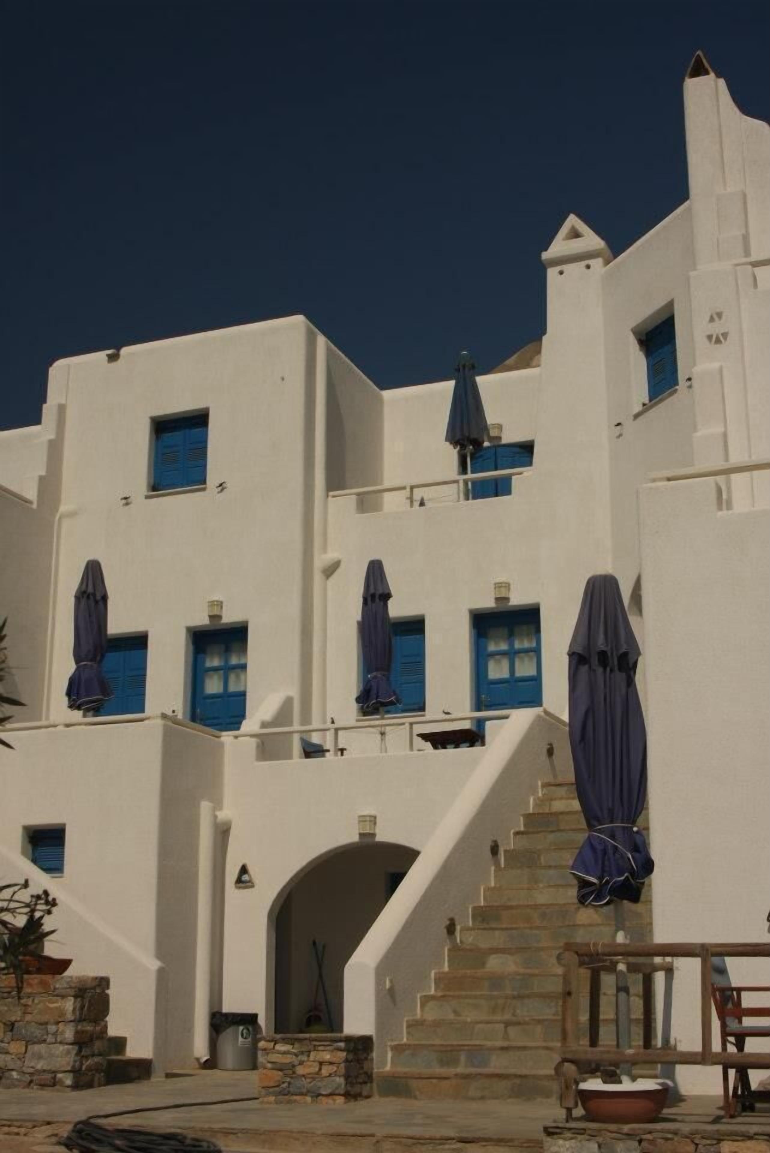 Um edifício branco com detalhes em azul, com escadaria e área de estar ao ar livre.