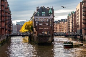 Um canal com um barco, edifícios com telhados verdes e uma ponte.