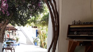 Quarto com uma mesa azul, uma planta em vaso com flores e uma escada que leva a um andar superior.