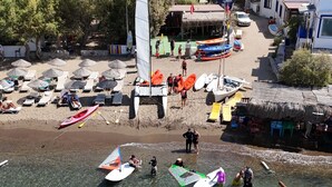 Uma área costeira com águas cristalinas, guarda-sóis de praia e pessoas praticando atividades aquáticas.