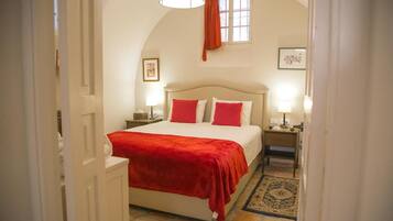 Um quarto com uma cama, duas mesas de cabeceira, uma janela com cortinas e um tapete.