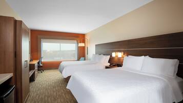 Quarto de hotel com duas camas, uma escrivaninha e uma janela grande.