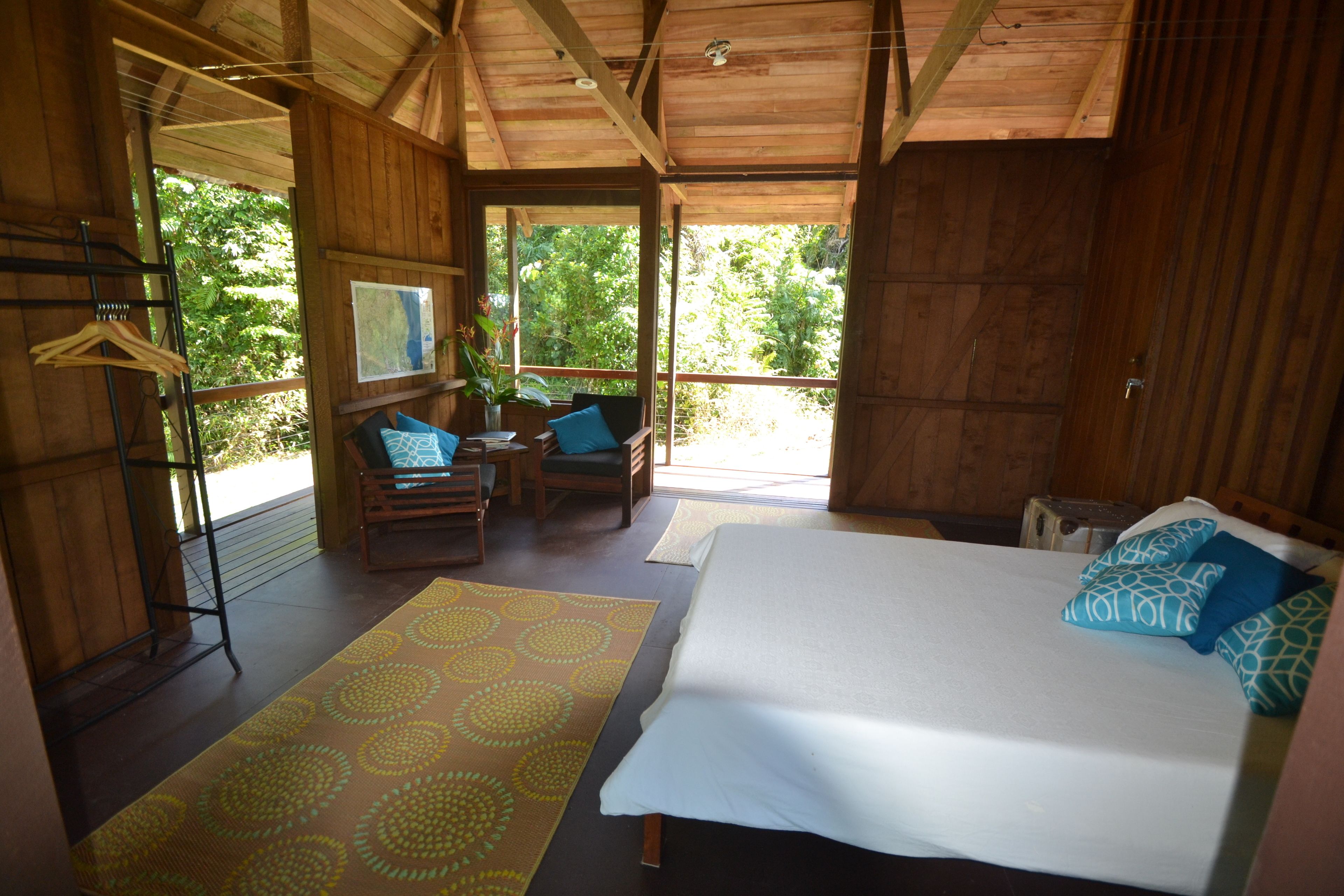 Uma cabana de madeira com uma cama, uma cadeira, uma mesa e um mapa na parede.