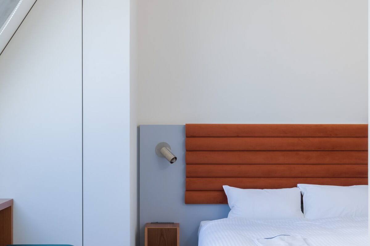 Quarto moderno com cabeceira de madeira, mesa de cabeceira e criado-mudo.