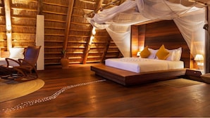 Um quarto acolhedor com uma cama de madeira, uma cadeira e teto de colmo.