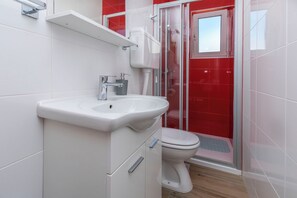 Um banheiro com pia branca, vaso sanitário e box de vidro.