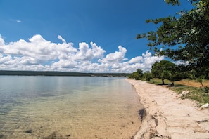 Uma praia com águas cristalinas, areia dourada e árvores.