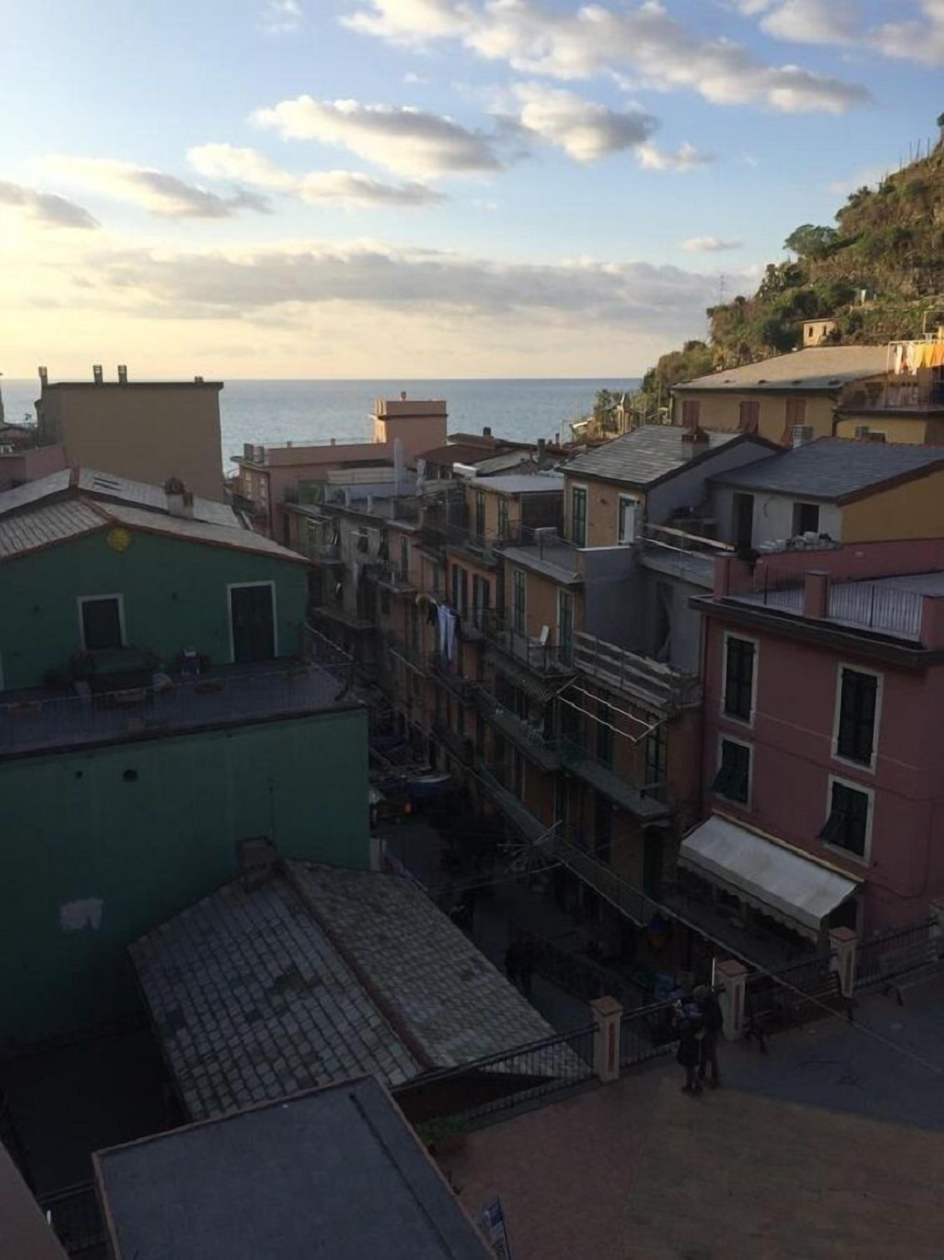 Uma vila costeira com edifícios ao longo da orla, apresentando varandas e uma área para pedestres.