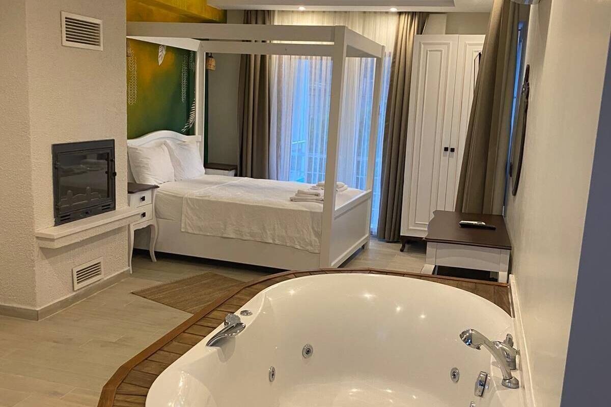 Quarto de hotel moderno com uma banheira grande, uma cama com dossel e uma televisão.