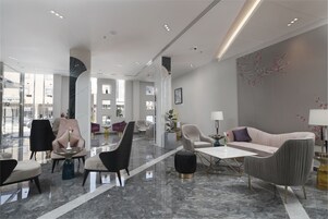 Um hall moderno com piso de mármore, mobiliário contemporâneo e uma grande janela com vista para a rua.