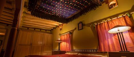 Quarto com cama, guarda-roupa de madeira e teto com padrão decorativo.