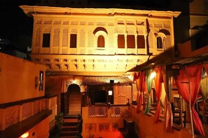 Um edifício tradicional com detalhes arquitetônicos elaborados e uma varanda com cortinas coloridas.