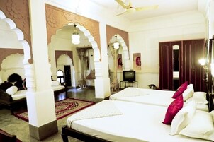 Quarto de hotel com duas camas, televisão e ventoinha no teto.