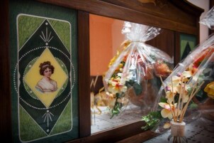 Um retrato emoldurado com moldura decorativa, um espelho com arranjos florais e um pequeno vaso com flores.