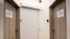 Duas portas identificadas como “Studio com Vista para a Rua” e “Studio com Vista para o Jardim”, com um toldo branco no meio.