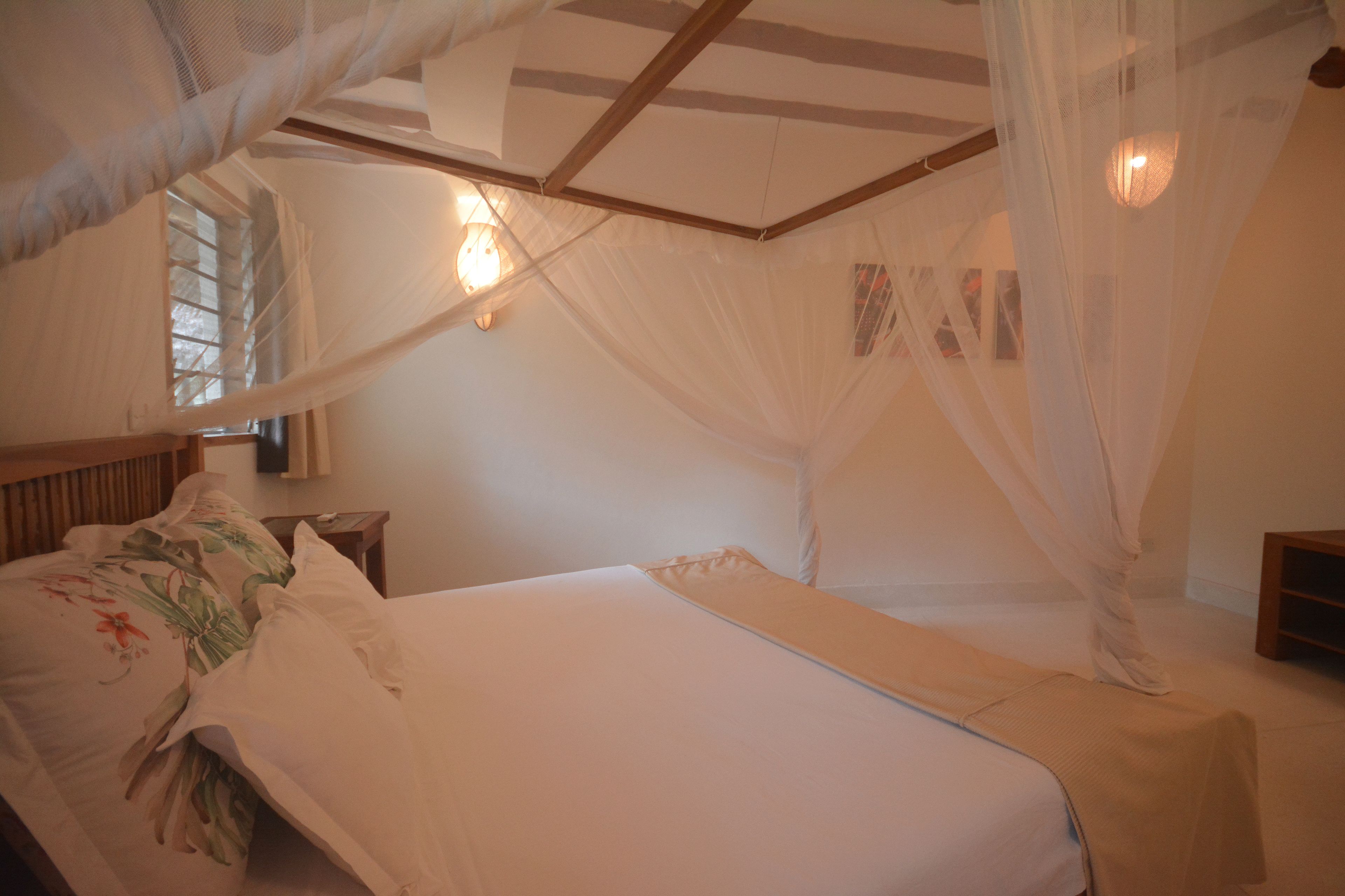 Um quarto com uma cama, mesa de cabeceira e janela com cortinas.