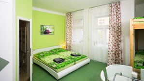 Quarto com cama, cadeira, janela com cortinas florais e porta.