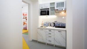 Cozinha moderna com micro-ondas, chaleira e cafeteira no balcão, e pia com torneira.