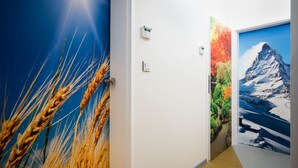 Um corredor com um mural de um campo de trigo à esquerda, uma cena de floresta ao centro e uma paisagem de montanha à direita.