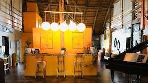 Uma área de bar com balcão central, três banquetes e um piano.
