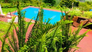 Uma piscina rodeada por vegetação exuberante e uma vista panorâmica de colinas ondulantes.