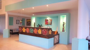 Balcão de recepção com design floral, balcão de check-in e uma obra de arte na parede.