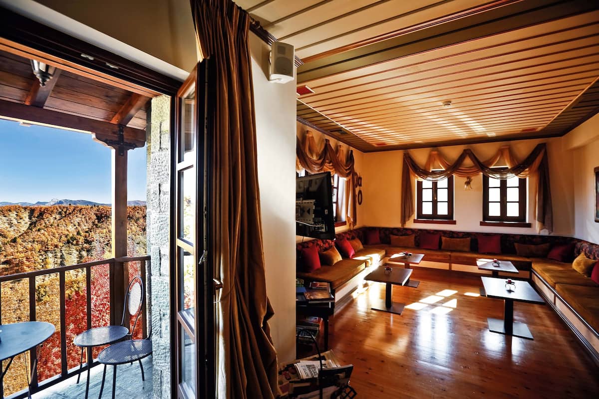 Uma sala ampla com teto de madeira, janelas grandes e uma varanda com vista panorâmica.