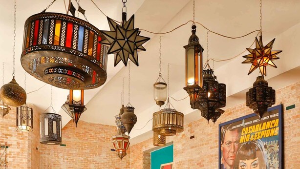 Uma sala de estar aconchegante com parede de tijolos, sofá, poltronas estampadas e tapete vermelho.