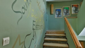 Uma escadaria com um muro pintado à mão, decorado com diversas inscrições, e um corrimão de madeira.