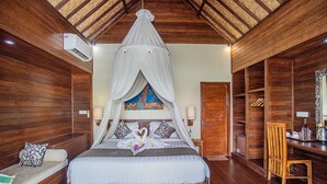 Quarto de madeira com cama, um banco, uma cadeira, escrivaninha e espelho.