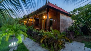 Uma casa de madeira com telhado de telhas, rodeada por vegetação exuberante e um jardim bem cuidado.