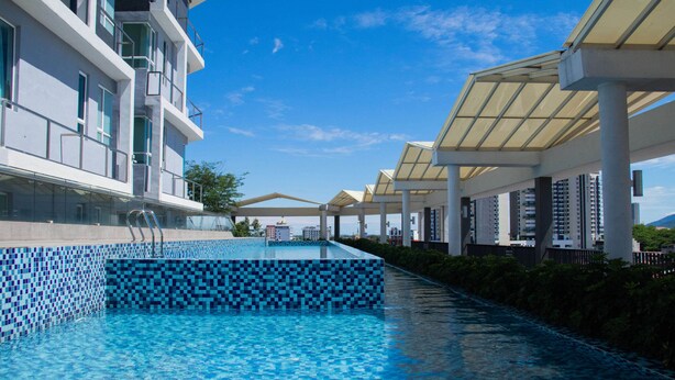 Piscina com borda azulejada, rodeada por uma galeria coberta e um edifício com varandas.