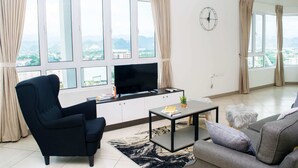 Uma sala de estar moderna com uma janela grande, uma televisão de tela plana, um sofá, uma poltrona e uma mesa de centro.
