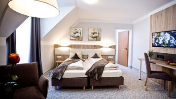 Quarto de hotel moderno com cama, escrivaninha, televisão e obras de arte na parede.
