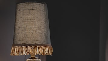 Uma luminária de mesa com cúpula texturizada e base trançada, sobre uma superfície escura.