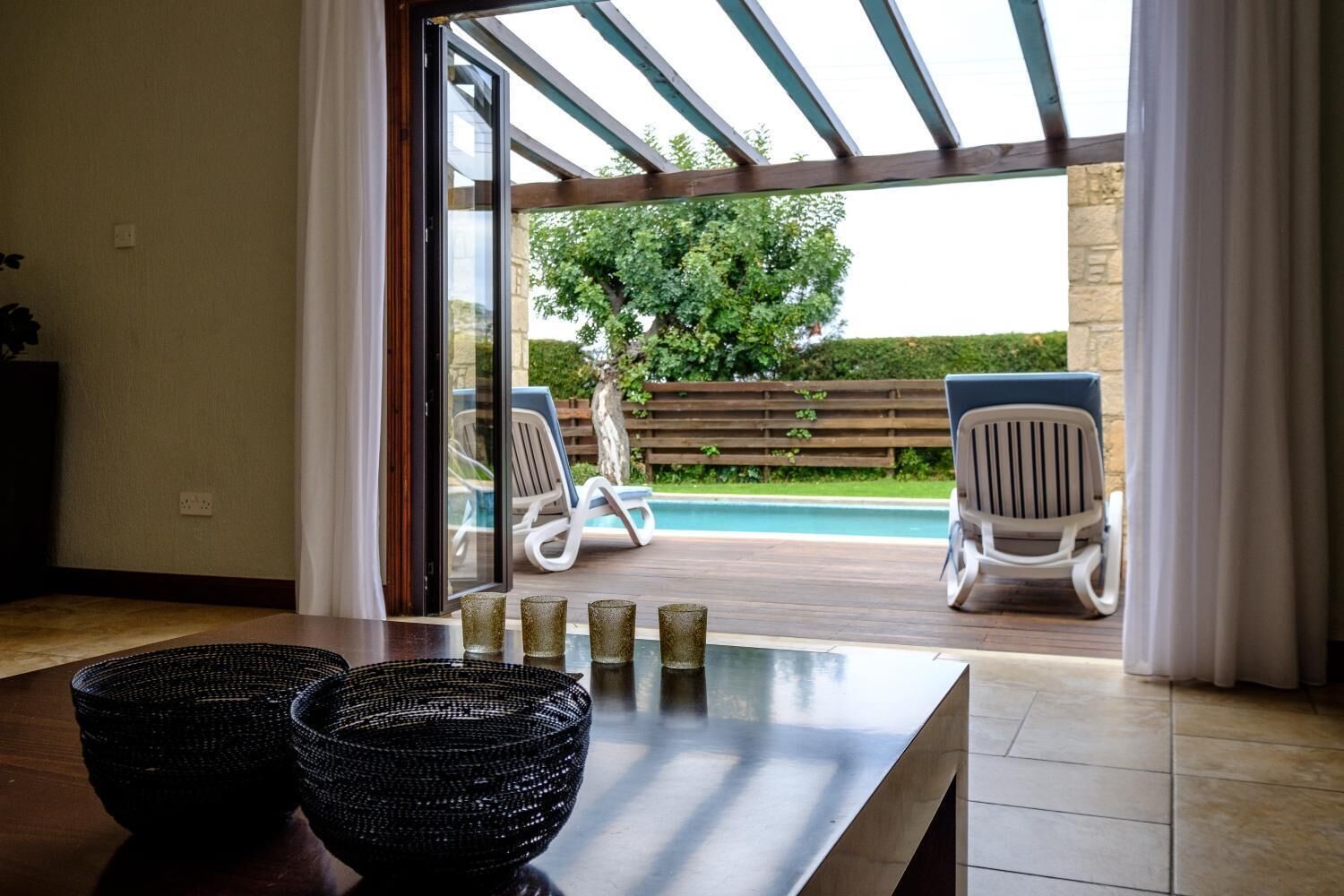 Espaço moderno e interno com porta de vidro que dá para área externa com piscina e espreguiçadeiras.