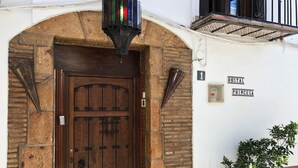Uma entrada rústica com porta de madeira, um candeeiro pendurado e uma placa indicando 
